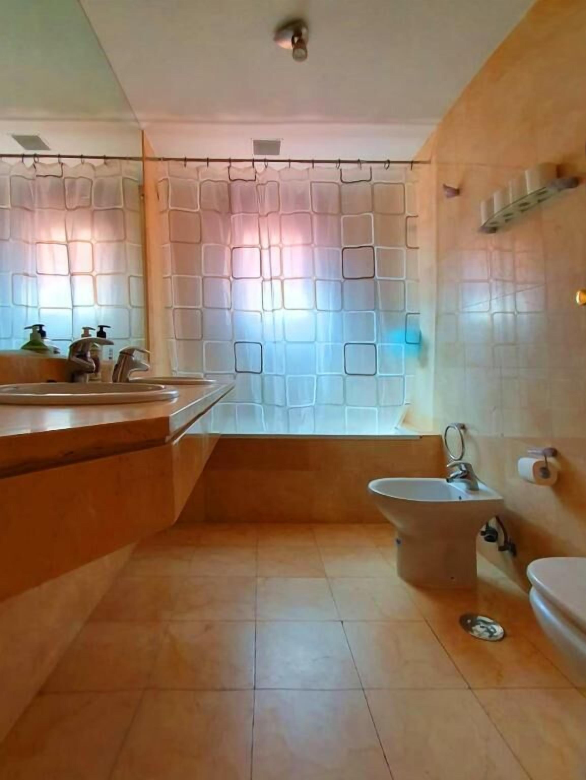 Casa de banho com chuveiro, sanita e lavatório.