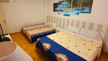 Quarto de hotel com duas camas, uma janela grande e parede com três quadros.