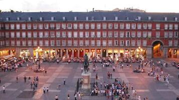 Pátio histórico com uma estátua central, rodeado por edifícios com vários andares e varandas.