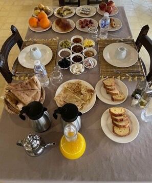 Uma mesa de café da manhã com diversos alimentos, pratos e utensílios.