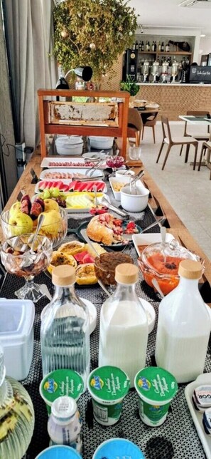 Disposição de buffet com diversos alimentos, bebidas e acompanhamentos.