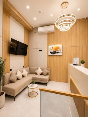 Uma área de recepção moderna, com um sofá, uma mesinha e um balcão de atendimento.