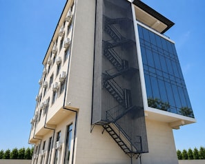 Um edifício moderno com fachada de vidro, escadaria de metal e várias unidades de ar condicionado.