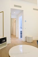 Quarto moderno e bem iluminado, com piso de mármore, uma mesa redonda branca e um cofre embutido.