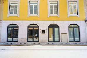 Um edifício com portas numeradas, uma placa indicando um hotel e um pavimento ladrilhado.