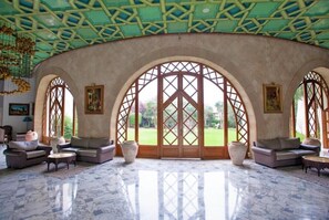 Um quarto espaçoso com teto alto, grandes janelas em arco e piso de mármore.