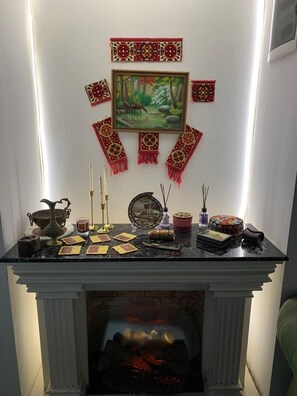 Lareira com mantelha decorada com vários objetos, incluindo velas, incenso e uma moldura com fotografia.