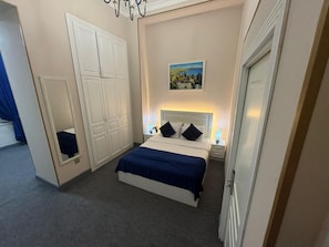 Quarto com cama, mesa de cabeceira, espelho, guarda-roupa e um quadro na parede.
