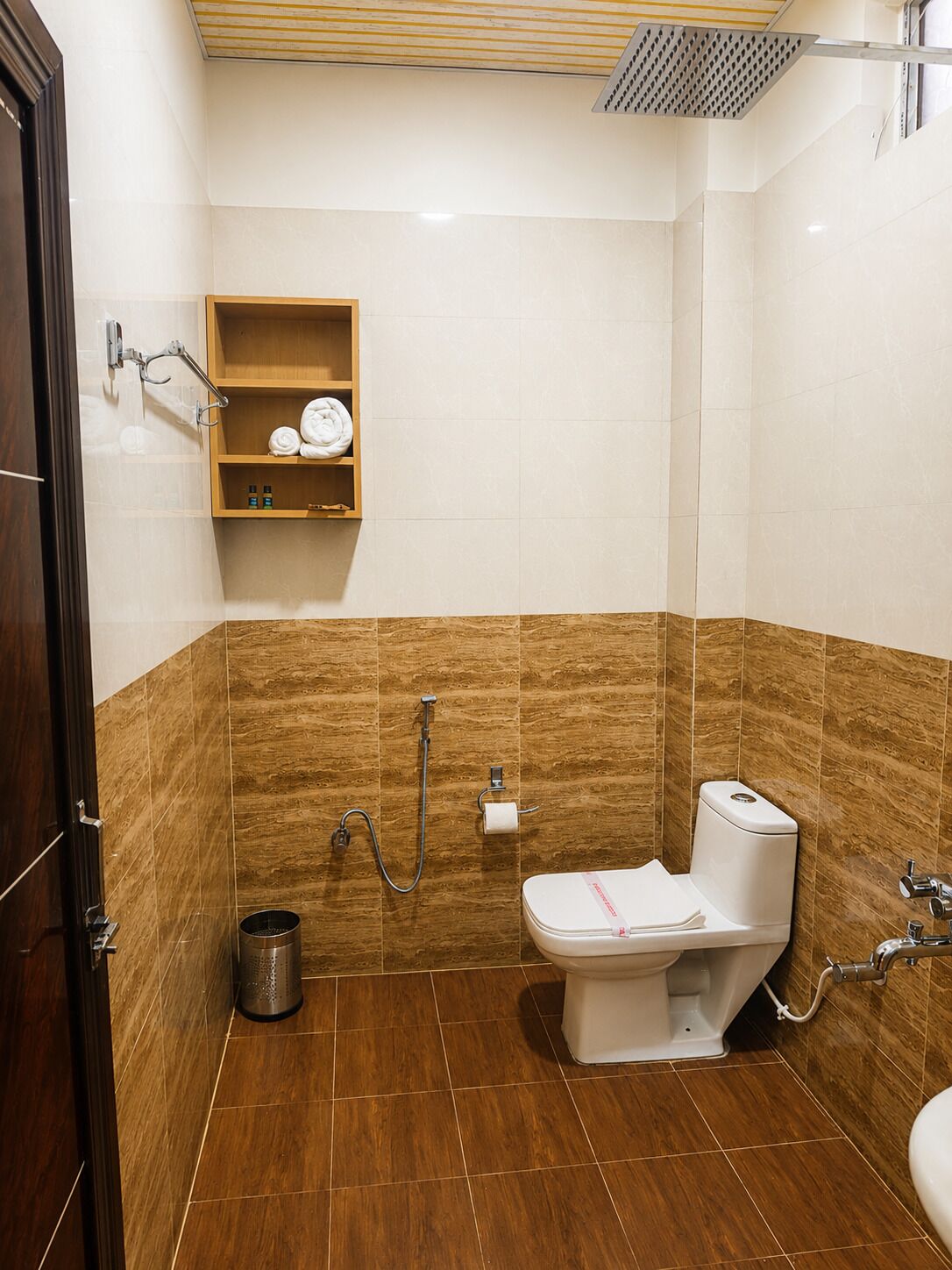 Um banheiro com vaso sanitário, chuveiro e porta-toalhas.