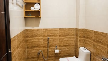 Um banheiro com vaso sanitário, chuveiro e porta-toalhas.