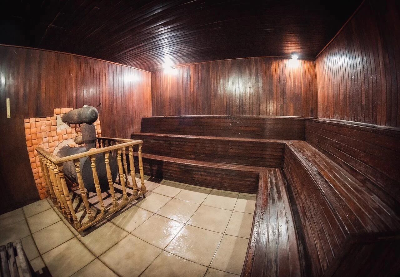 Quarto com painéis de madeira, parede de tijolos e um espaço com bancos.