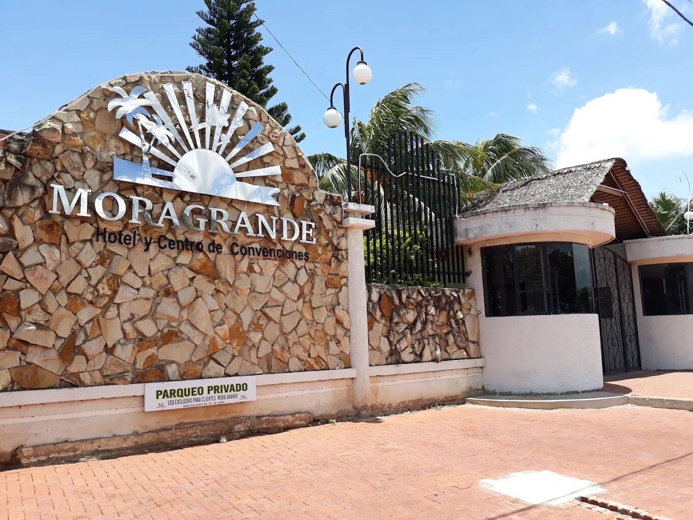 Entrada de hotel com parede de pedra e uma placa que diz 'MORAGRANDE Hotel y Centro de Convenciones'.
