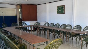 Uma sala de conferências com uma mesa comprida e várias cadeiras, um quadro branco e uma pintura na parede.