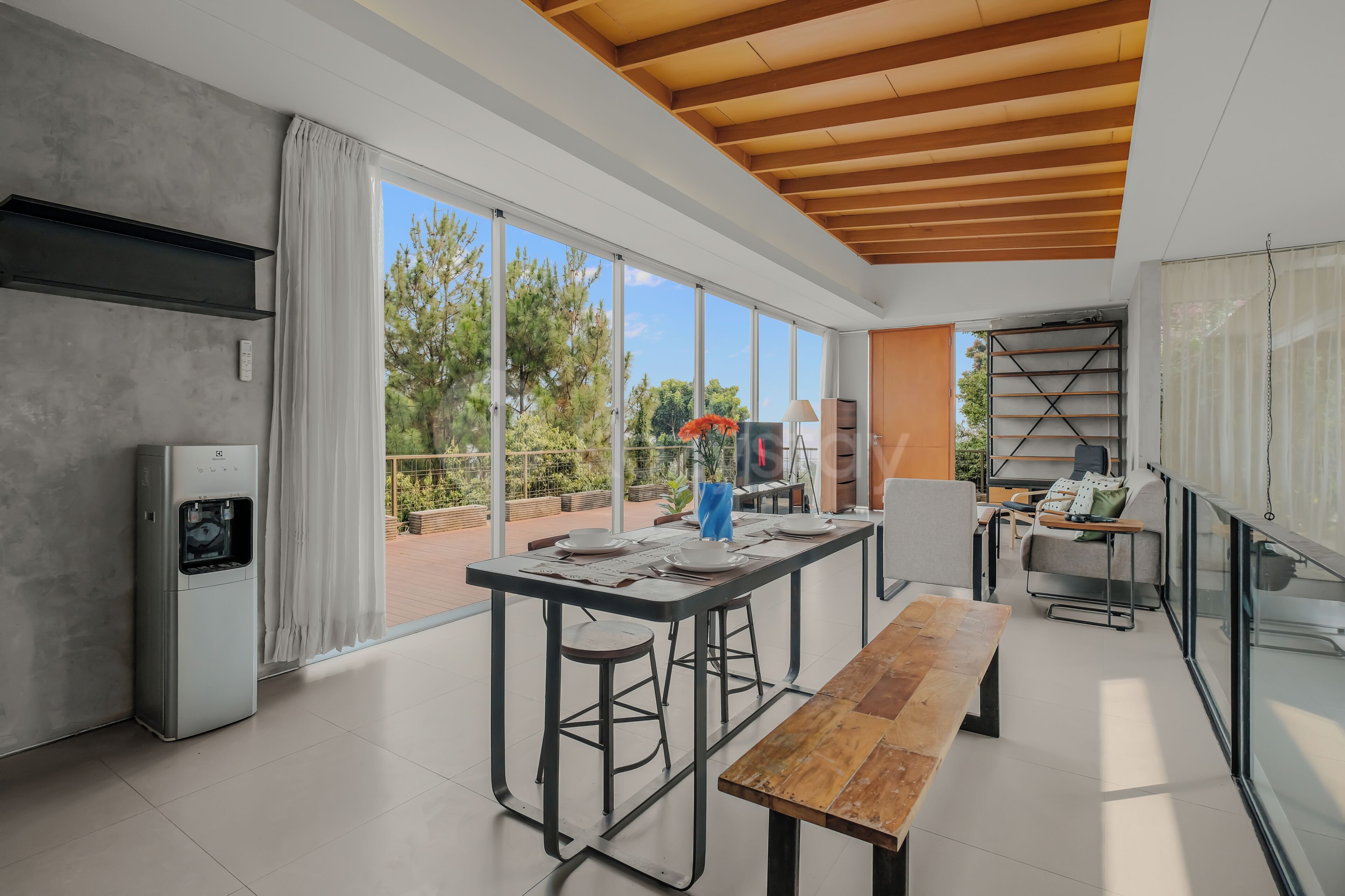 Uma cozinha moderna com forno embutido, mesa de jantar com cadeiras e grandes janelas com vista para o exterior.