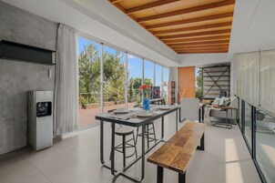 Uma cozinha moderna com forno embutido, mesa de jantar com cadeiras e grandes janelas com vista para o exterior.