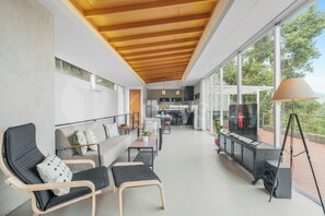 Um espaço de estar moderno com sofá, cadeiras, área de refeições e cozinha.