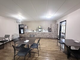Uma sala de conferências com bancada de mármore, cadeiras pretas e piso de madeira.