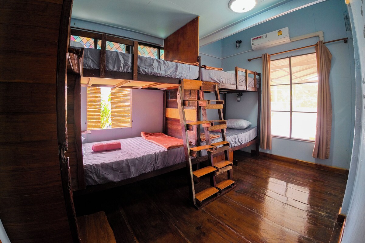 Quarto com beliche, escada, janela com persianas e ar condicionado.