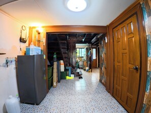Corredor com geladeira, bebedouro e escada que dá acesso a outro quarto.