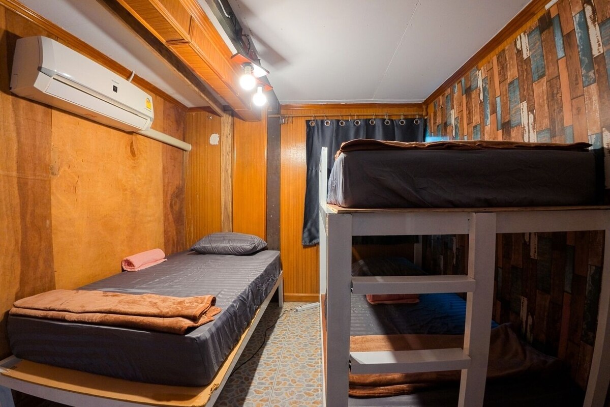 Quarto compacto com beliche, cama de solteiro e ar condicionado integrado.