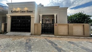 Um edifício com uma placa indicando 'Kothari Guest House' e uma entrada com portão.