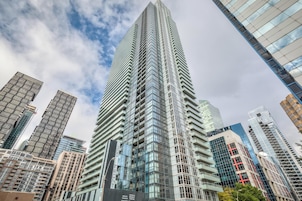Um edifício alto com fachada de vidro moderna, cercado por outros edifícios imponentes.