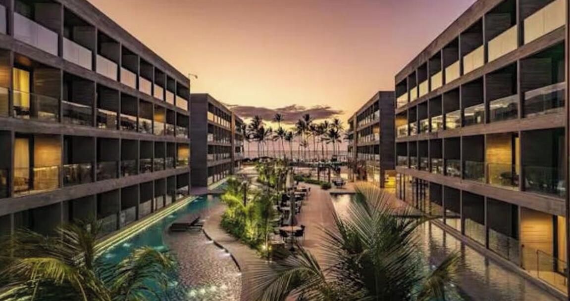 Um hotel moderno com piscina central, área de estar externa e vista para o pôr do sol.