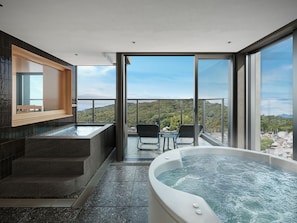 Uma casa de banho moderna com uma banheira grande, um banco de madeira e vista para a paisagem circundante.