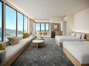Quarto de hotel moderno com uma grande janela, um sofá, uma cama, uma pequena cozinha e vista para a cidade.