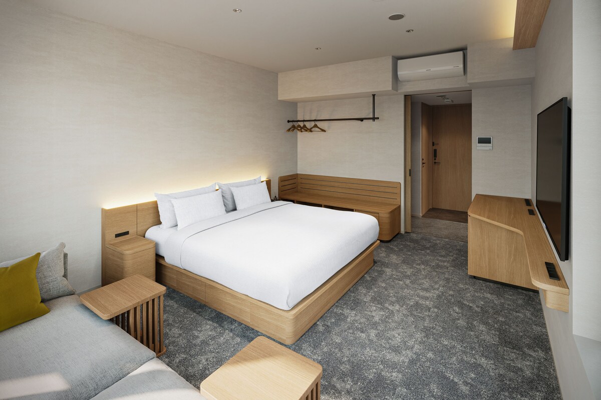 Quarto de hotel moderno com uma cama grande, mesas de cabeceira, uma TV e um closet espaçoso.