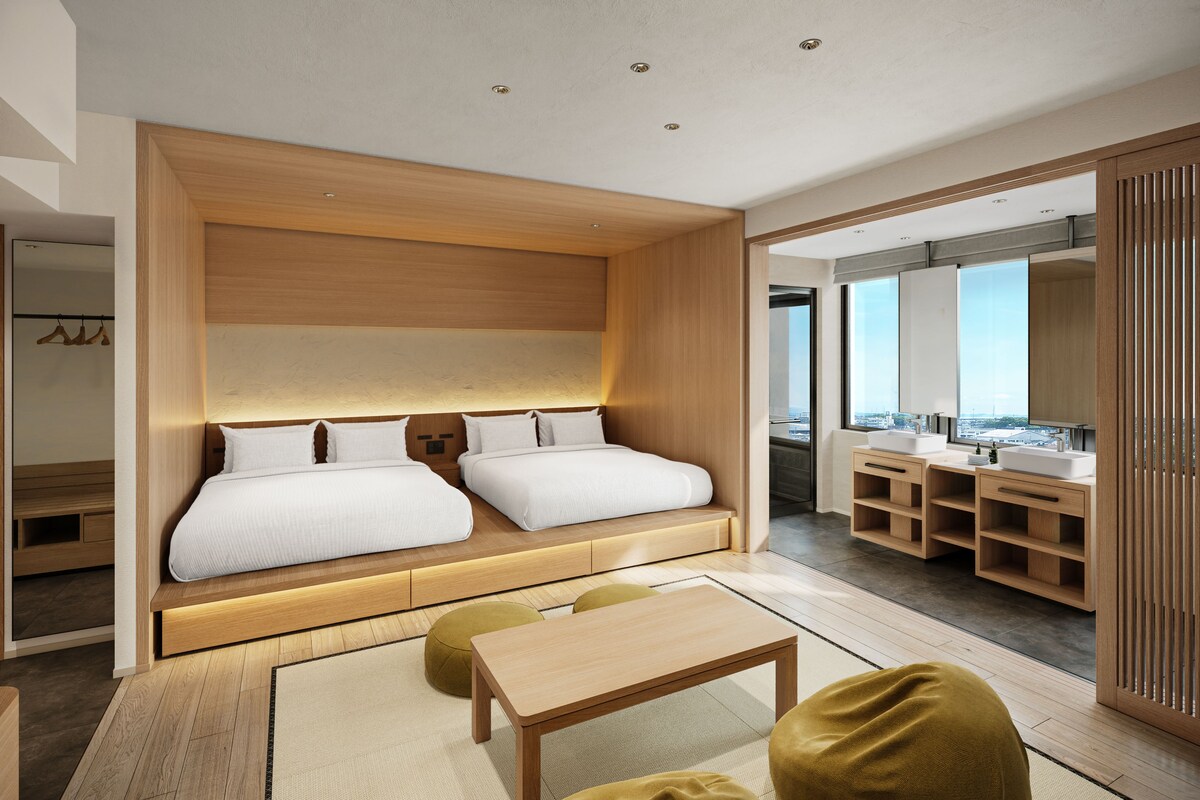 Quarto de hotel moderno com uma cama grande, uma escrivaninha e banheiro com espelho amplo.