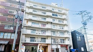 Um edifício residencial com vários andares, varandas, uma máquina de vendas automática e uma loja.