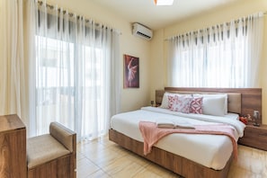 Quarto de hotel com cama, uma cadeira, um quadro e ar condicionado.