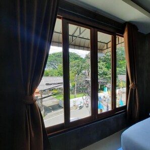 Um quarto com uma janela grande, cortinas e uma cama.