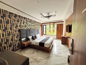 Quarto moderno com uma cama grande, cabeceira, mesa de cabeceira, ventoinha no teto e vista para o exterior através de uma janela.