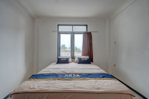Quarto de hotel com uma cama, uma janela com cortinas e vista para o exterior.