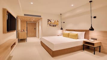Quarto moderno com uma cama grande, mesa de cabeceira e TV fixada na parede.