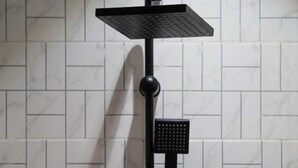 Chuveiro vertical preto com vários jatos em parede revestida de azulejos.