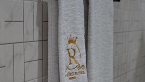 Duas toalhas brancas penduradas em um porta-toalhas, em frente a uma parede revestida de azulejos.
