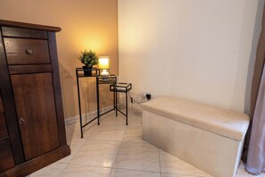 Um banheiro com um armário de madeira, uma mesinha com abajur e um vaso sanitário.