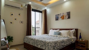 Quarto com cama grande, mesa de cabeceira, espelho e janela com cortinas.