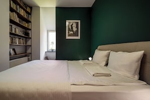 Quarto com uma cama grande, uma estante de livros e um quadro na parede.