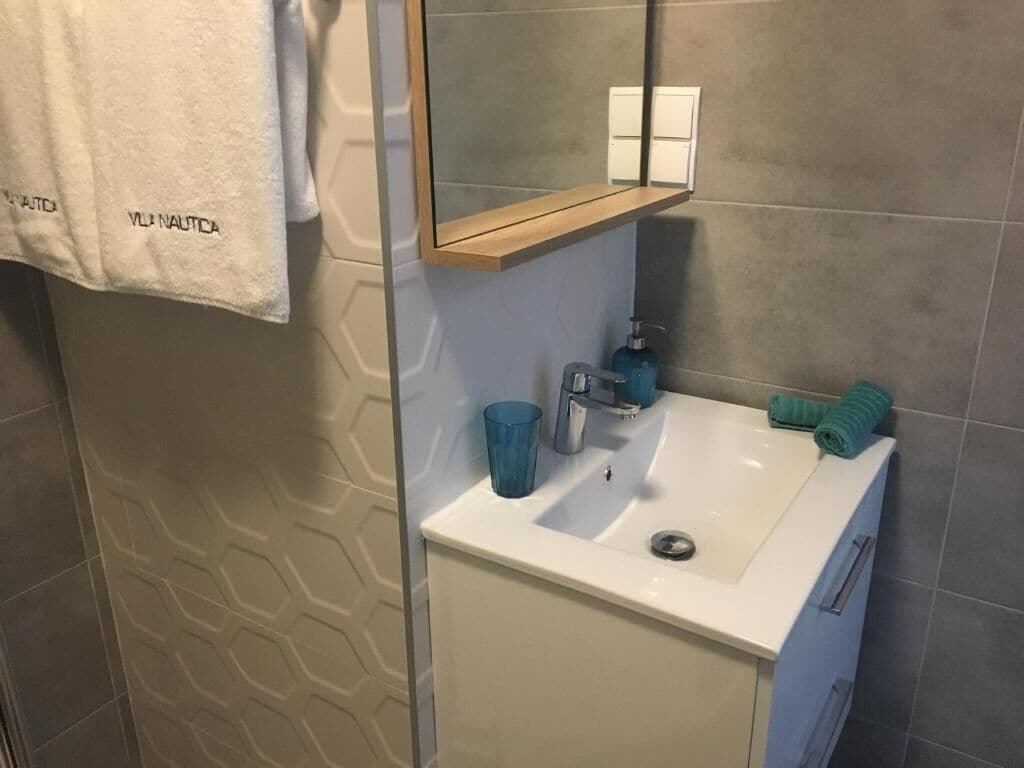 Uma casa de banho com uma pia branca, um espelho e uma toalha pendurada na parede.