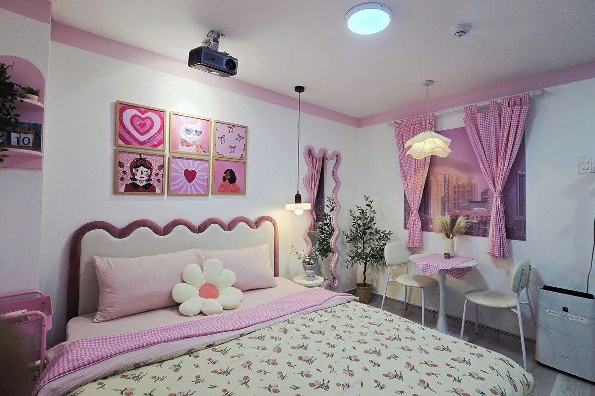 Quarto com cama, escrivaninha, cadeira e janela com cortinas.