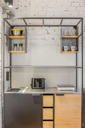 Uma cozinha compacta com bancada de aço inoxidável, cafeteira e chaleira.