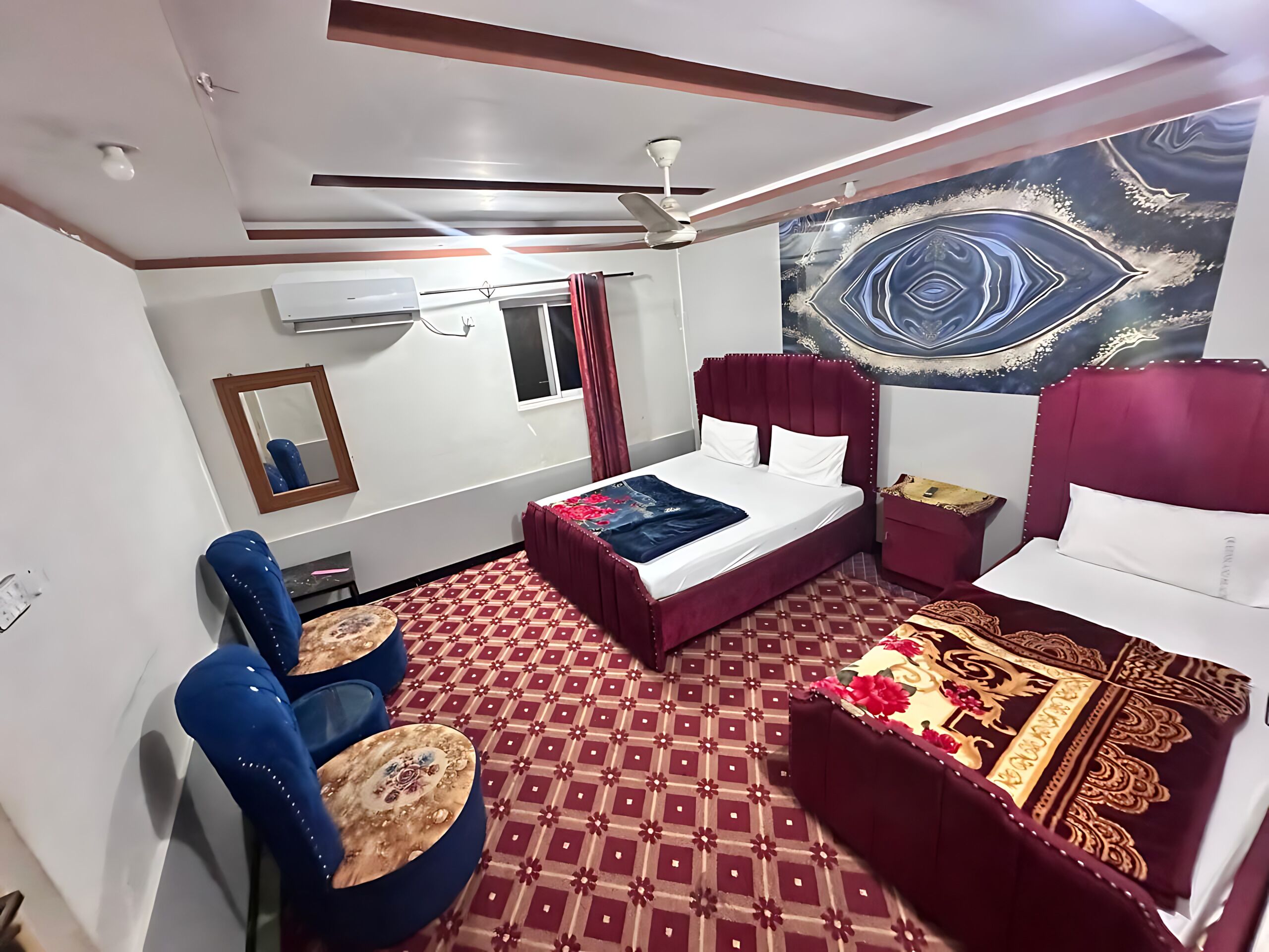 Quarto de hotel com uma cama, uma escrivaninha, uma cadeira e um ventilador de teto.