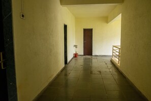 Um corredor com piso de azulejos, um vaso de planta e uma porta no final.