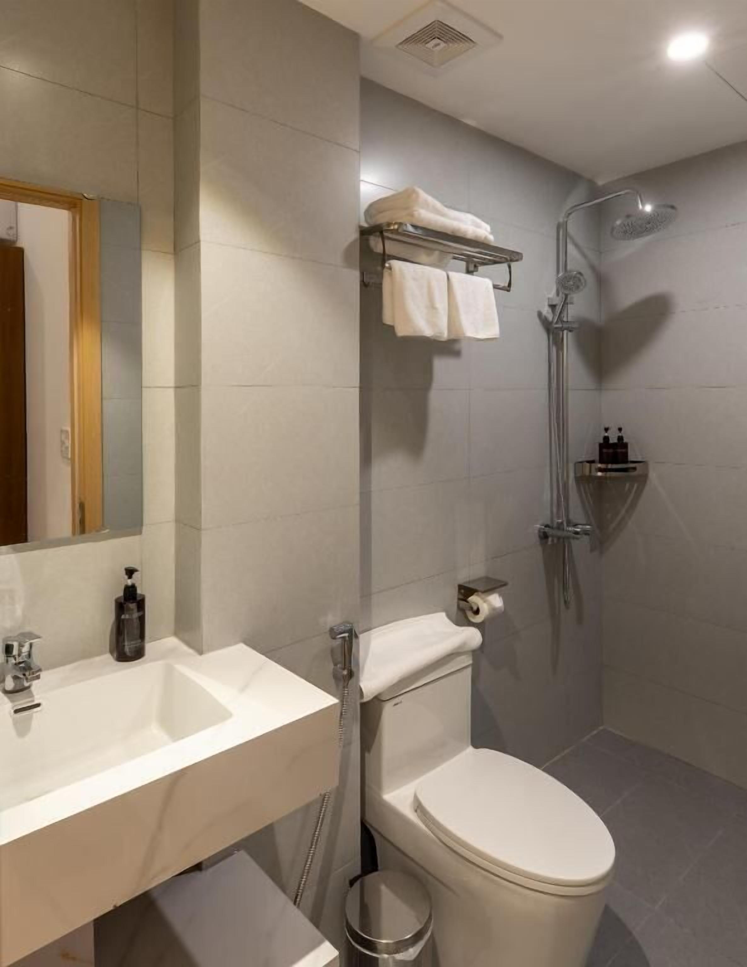 Uma casa de banho moderna com sanita, lavatório e chuveiro.