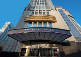 Um hotel com entrada destacada, uma Starbucks e céu claro.