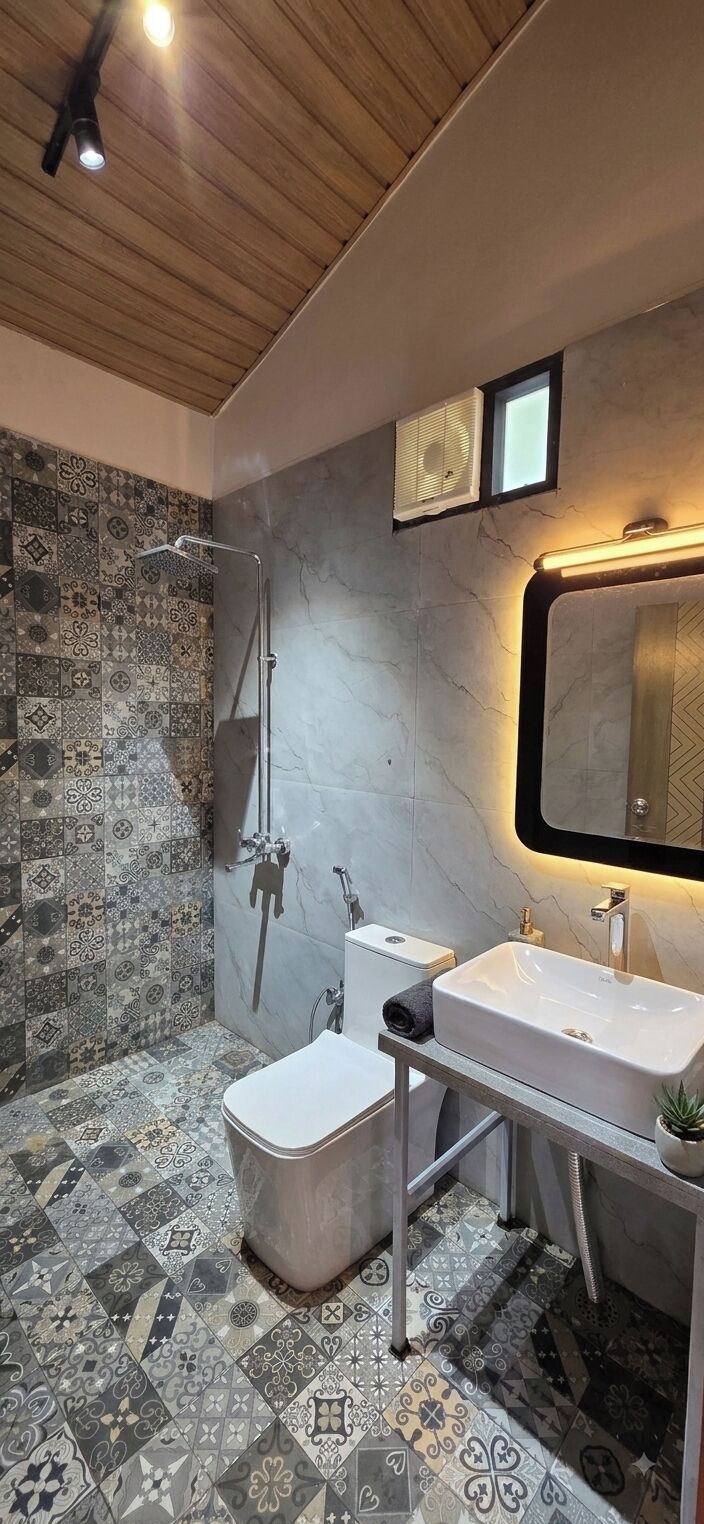 Casa de banho com chuveiro, duas pias, sanita e espelho.